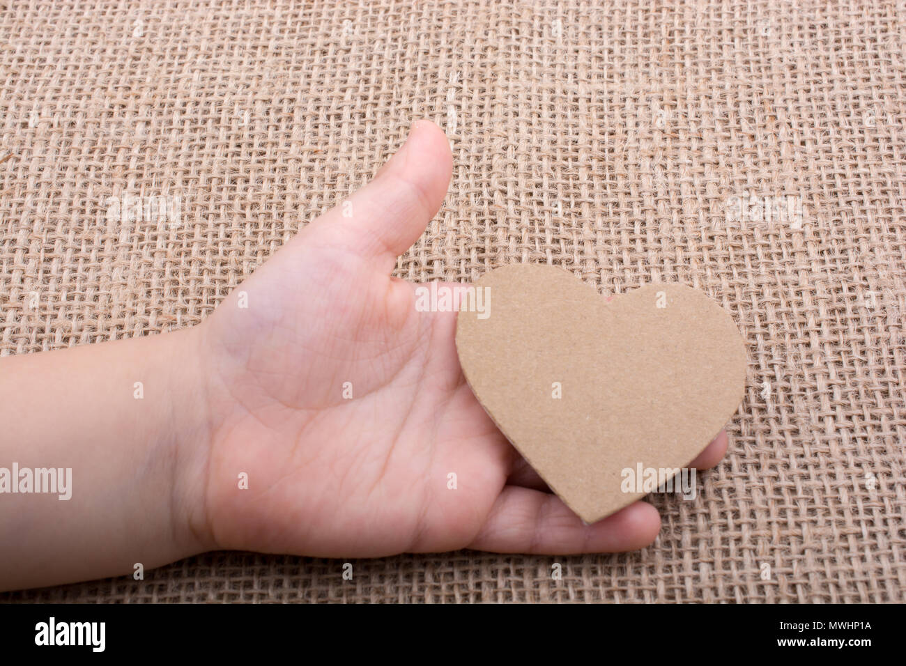 Heart shaped object in hand on a linen canvas Stock Photo - Alamy