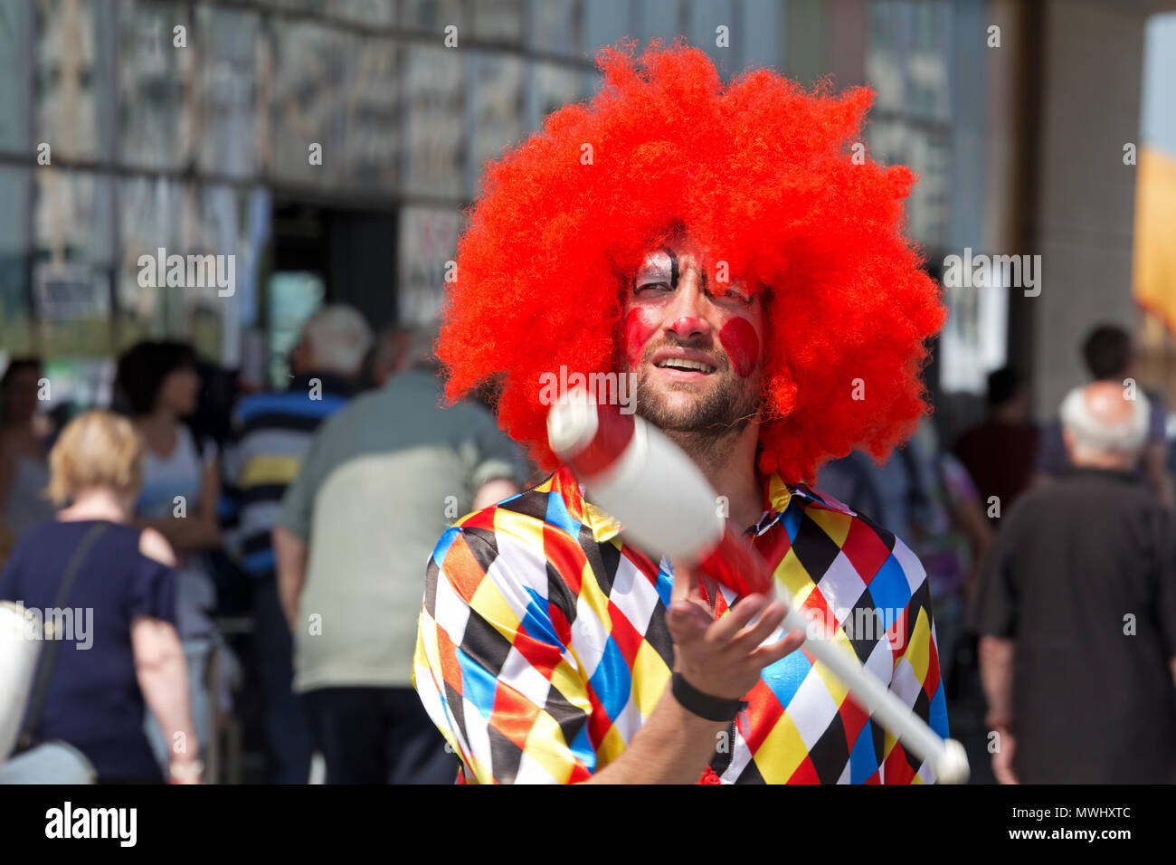 A street entertainer dressed as a clown entertains the crowds with some ...