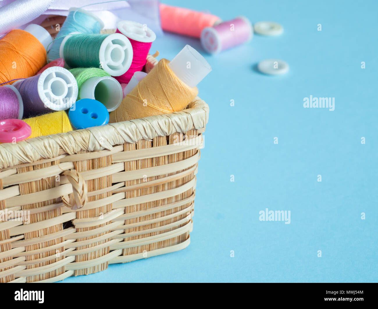 Colorful sewing buttons and thread in a wooden box on a blue background ...