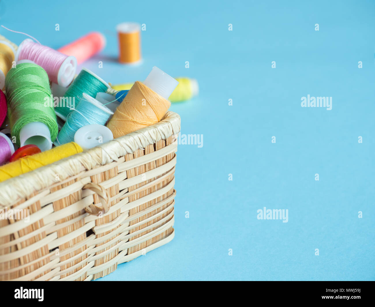 Colorful sewing buttons and thread in a wooden box on a blue background ...