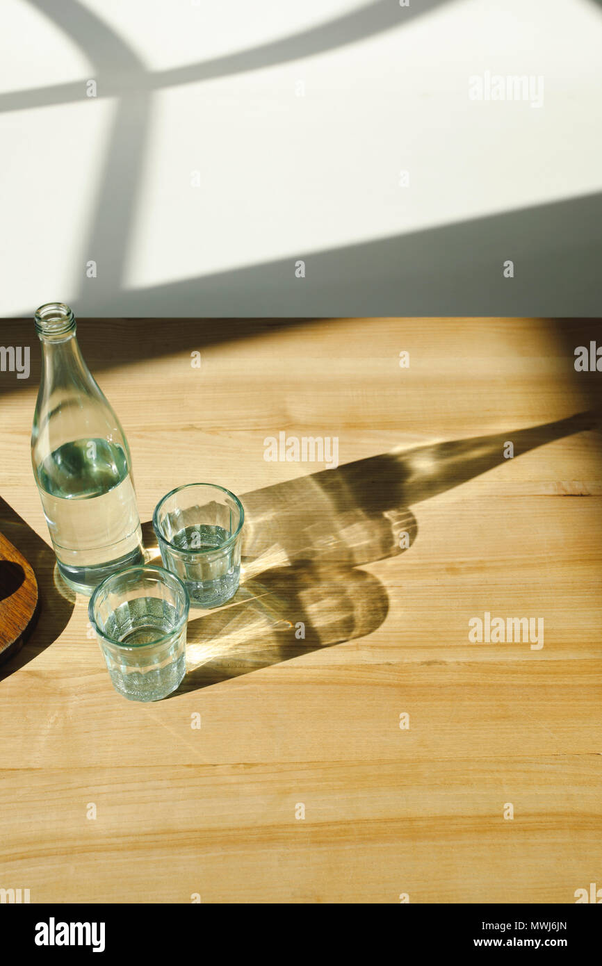 overhead view of transparent bottle and glasses with mineral water ...