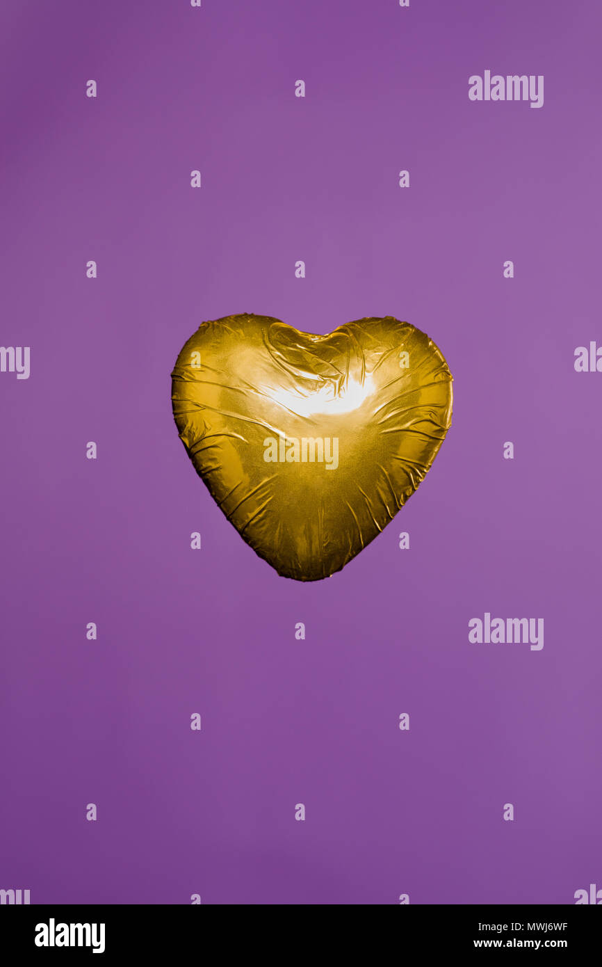 heart shaped candy in golden wrapper isolated on purple Stock Photo - Alamy