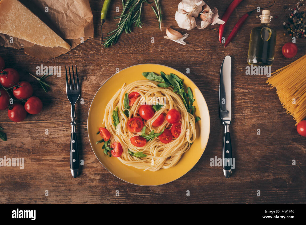 flat lay with traditional italian pasta with tomatoes and arugula in ...