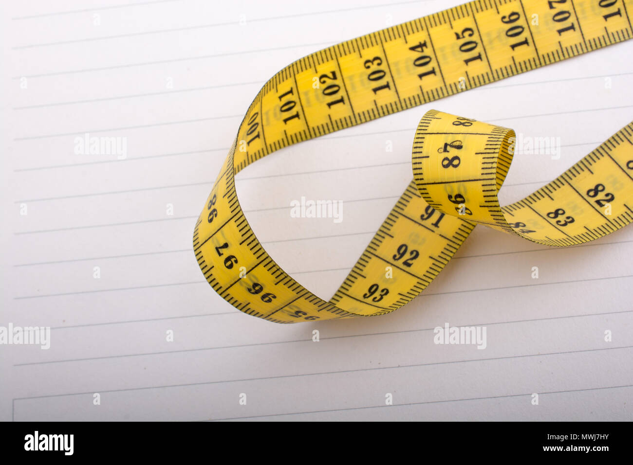 Yellow color measuring tape on lined paper Stock Photo - Alamy