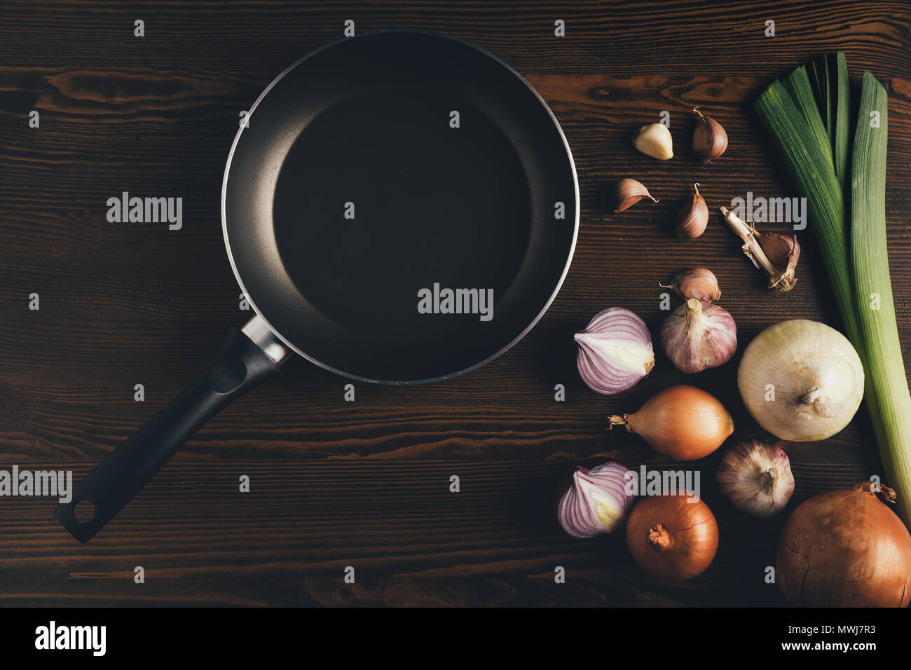 Top view of empty pan and onion with garlic on a table Stock Photo - Alamy