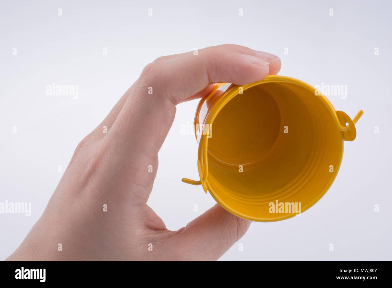 Hand holding a yellow bucket on a white background Stock Photo - Alamy