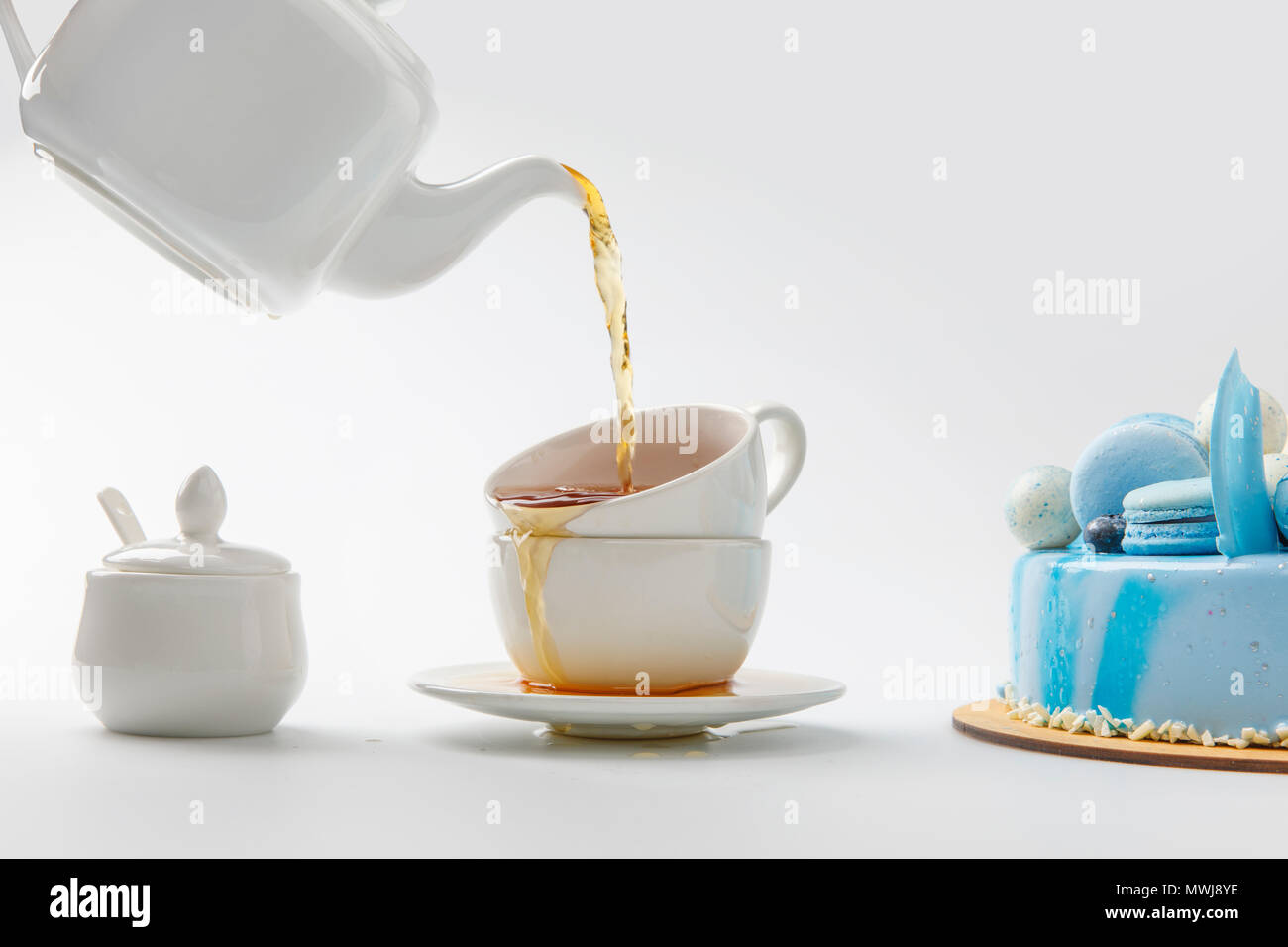 teapot pouring tea in cups near blue cake isolated on white Stock Photo ...