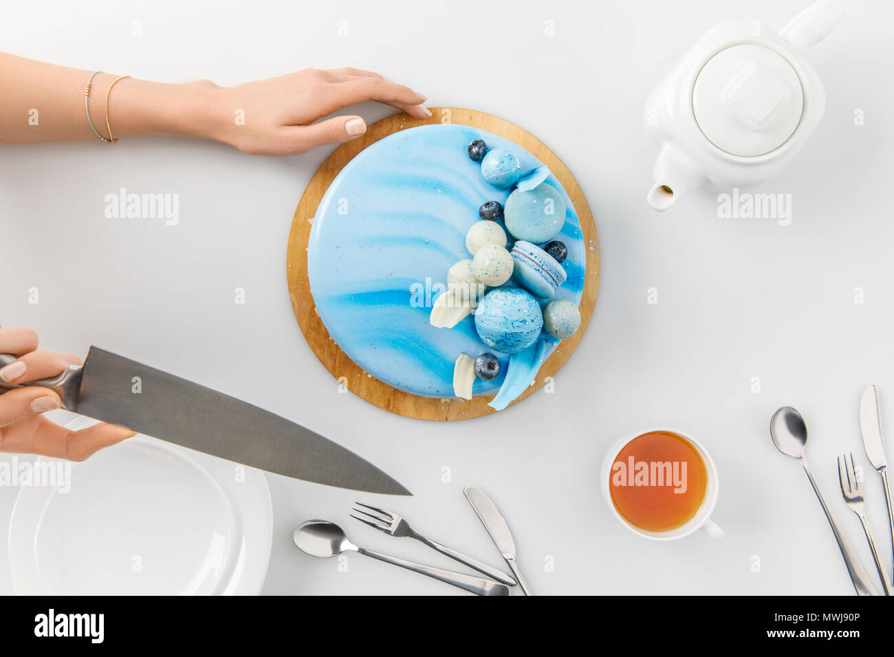 top view of cropped hands slicing cake on chopping board isolated on ...