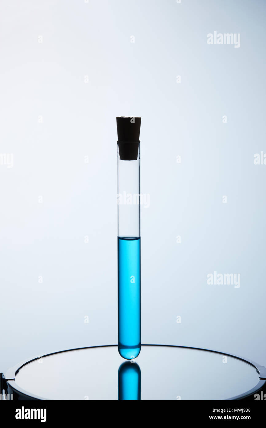 test tube filled with blue liquid standing on reflective surface Stock ...