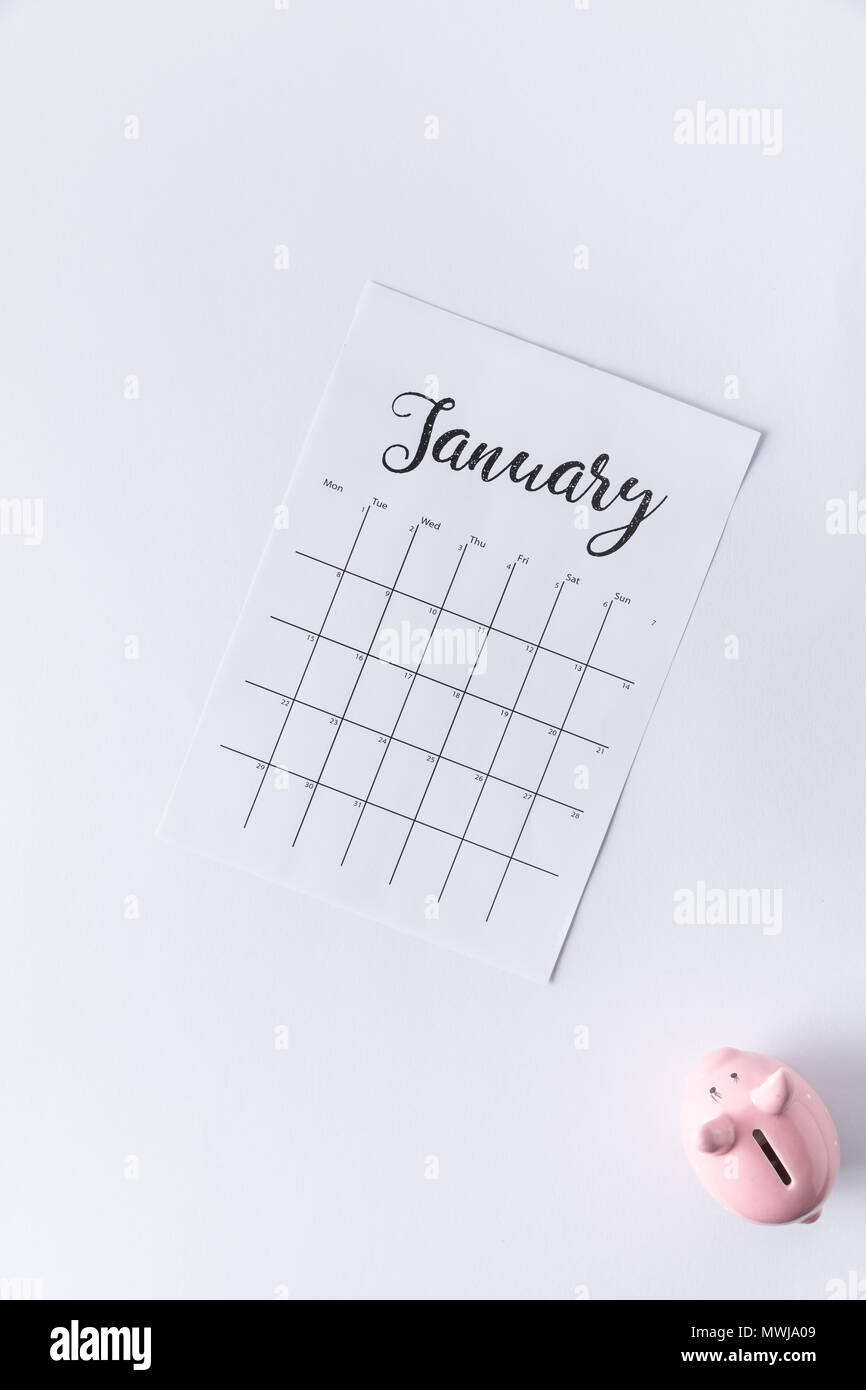 top view of part of calendar with january lettering and piggy bank ...