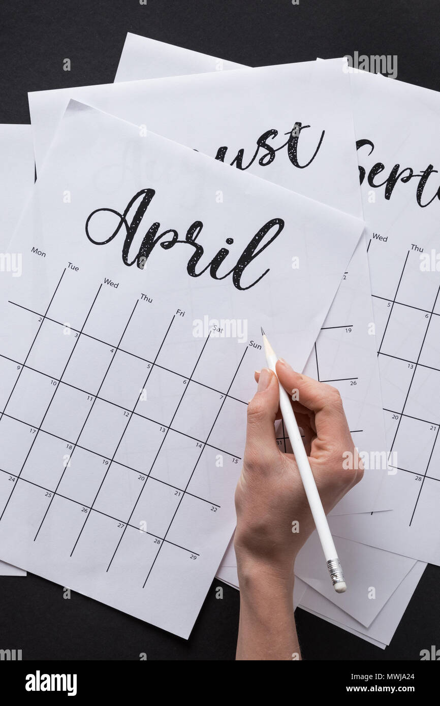 partial view of woman making notes in calendar isolated on black Stock ...