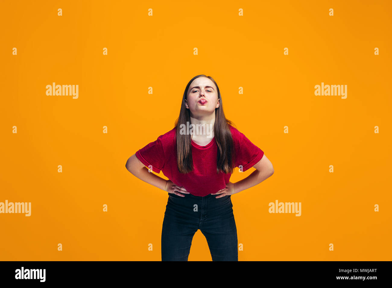 The happy teen girl standing and smiling against orange background ...