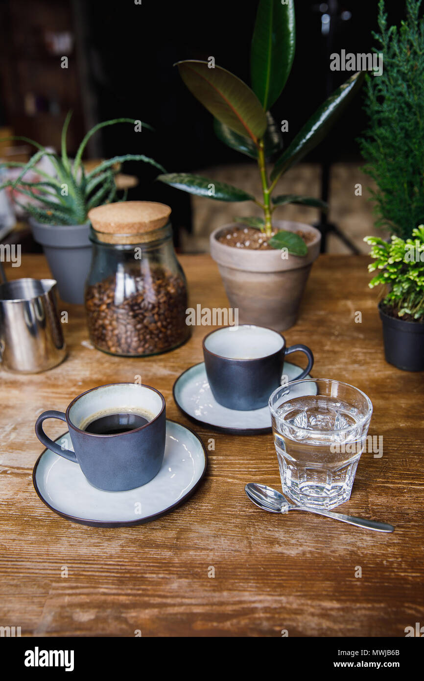 Cups of coffee and glass of water on cafe table Stock Photo - Alamy