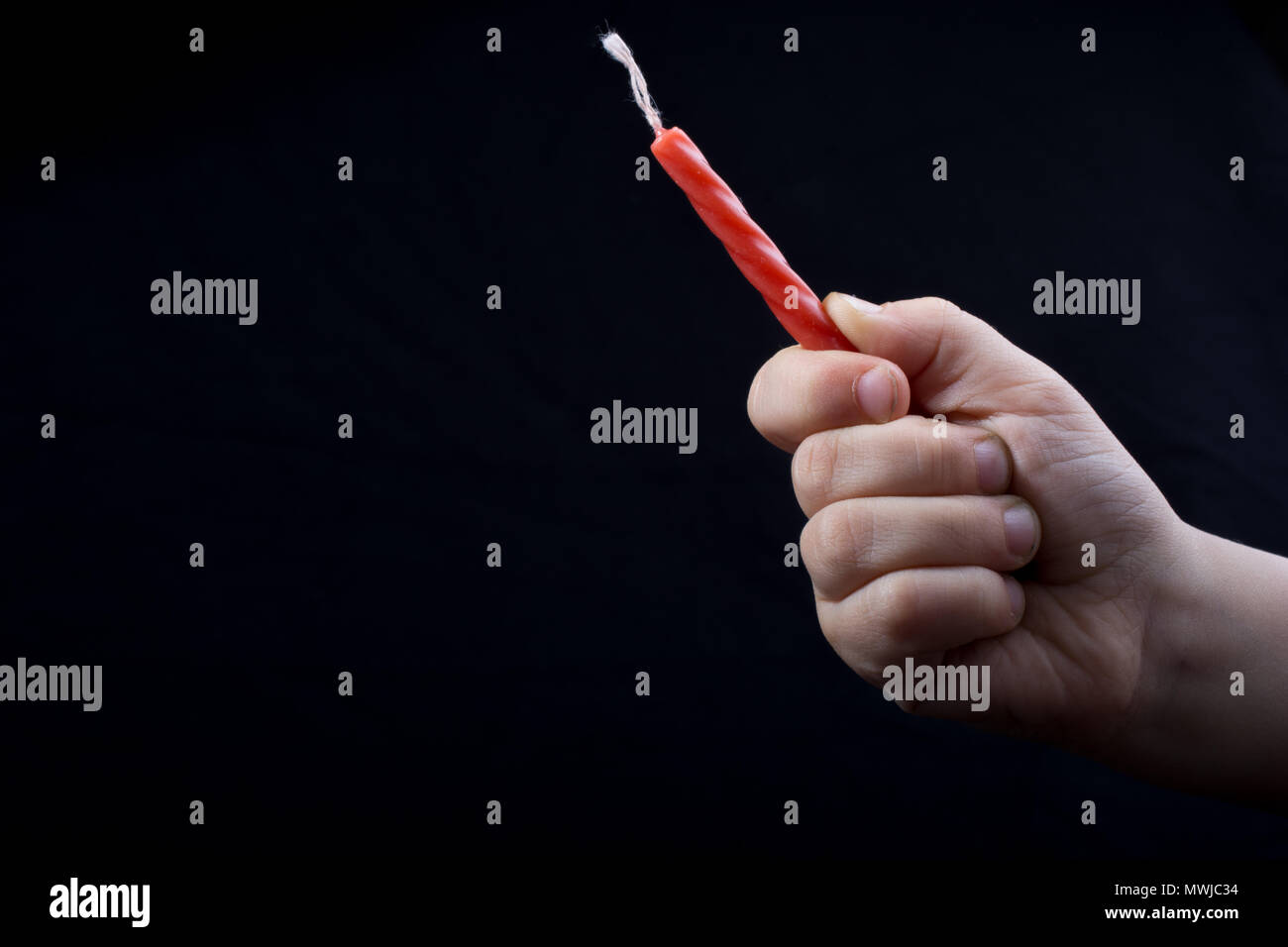 Colorful candle in hand on black background Stock Photo - Alamy