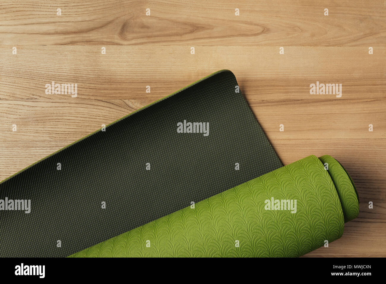 top view of green rolled yoga mat on wooden floor Stock Photo - Alamy