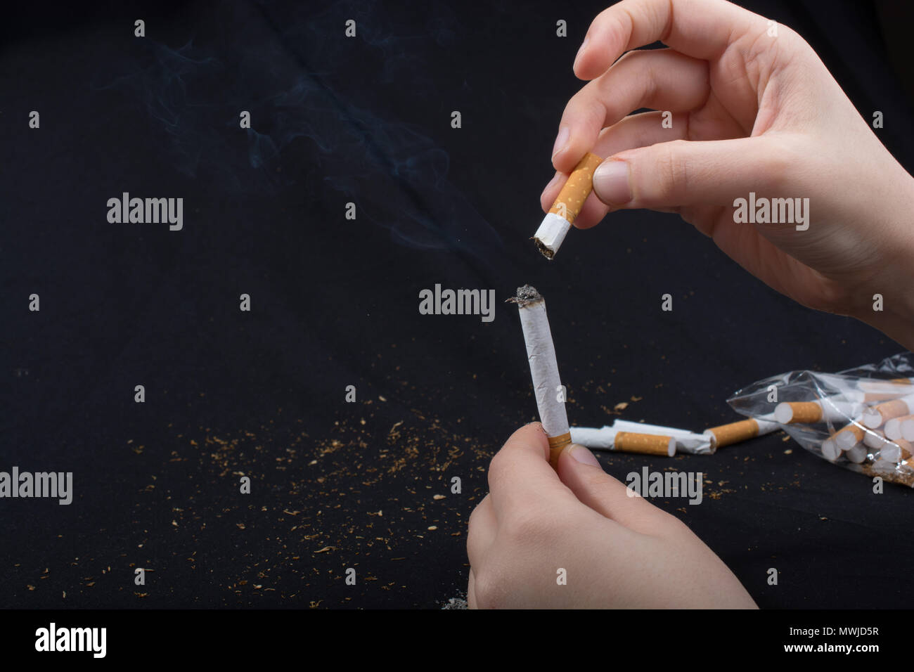 Hand is holding smoking cigarette with smoke around Stock Photo - Alamy