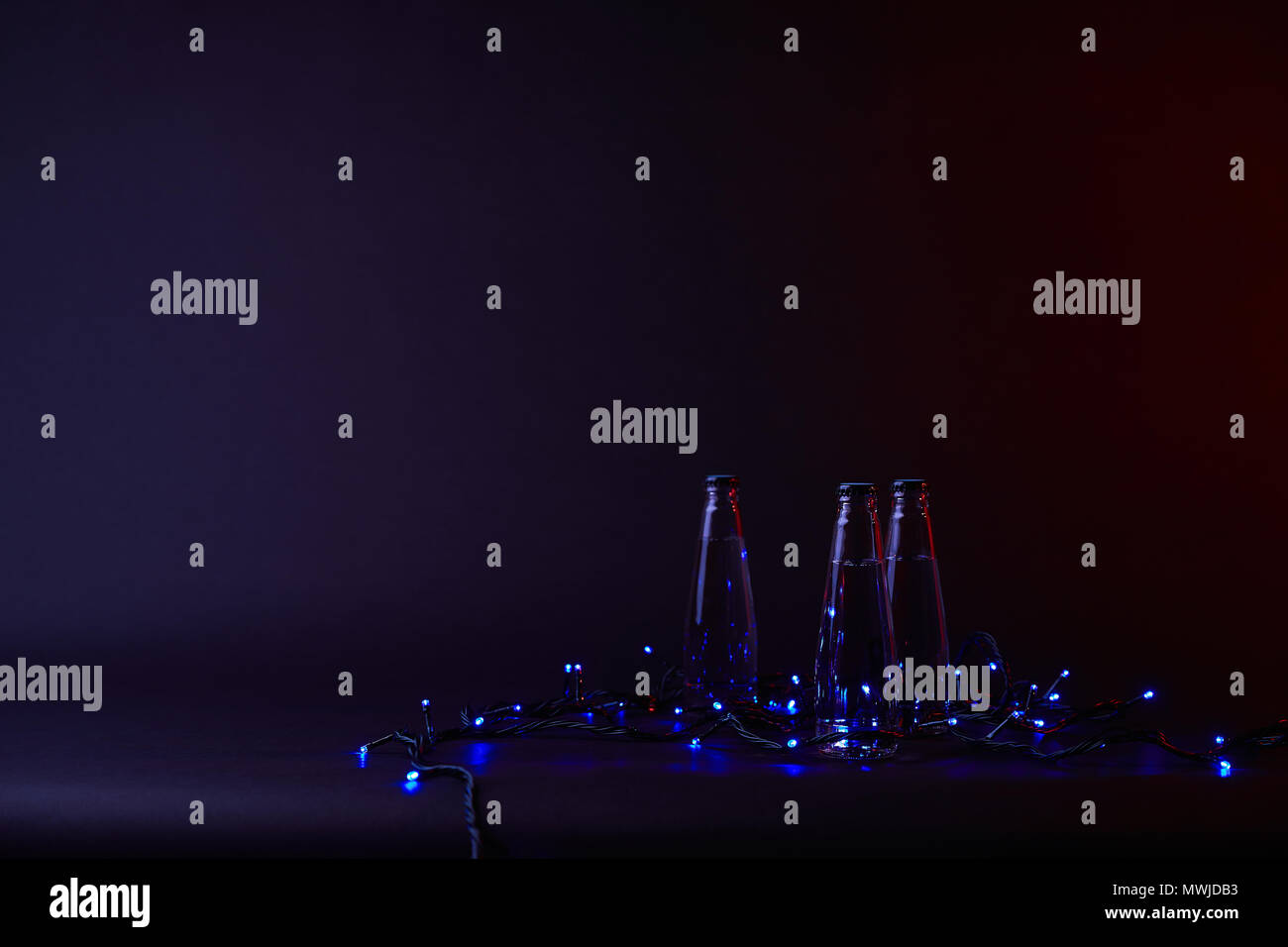 three closed bottles of water with blue garland on dark surface Stock ...