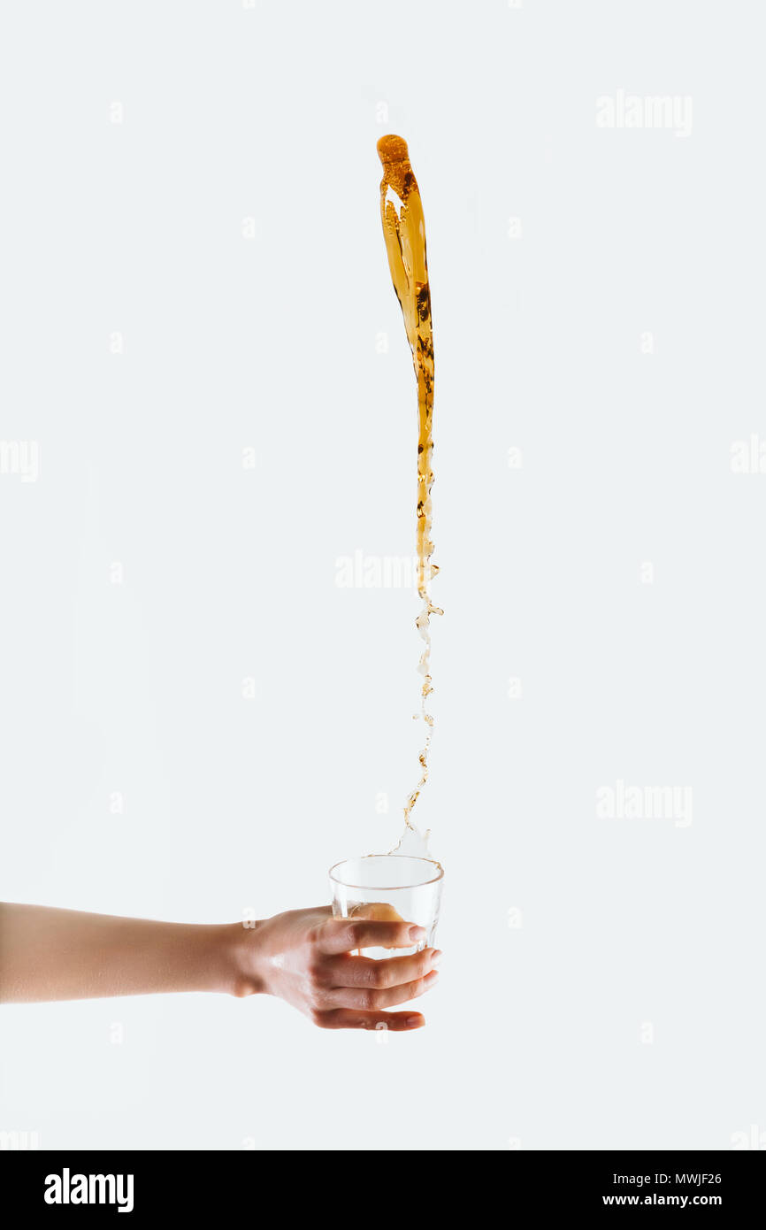 cropped view of hand holding glass and big splash of coffee, isolated ...