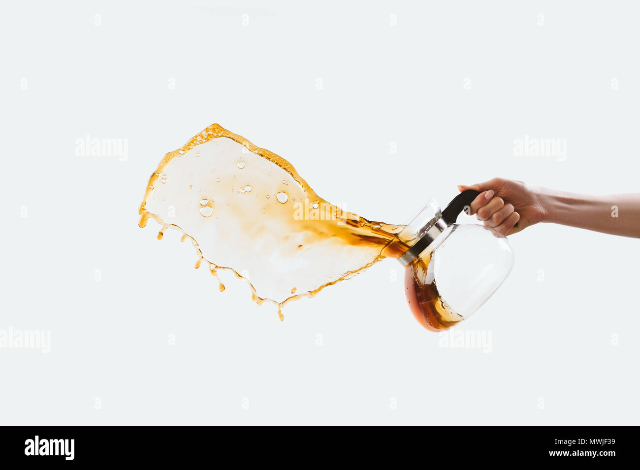 cropped view of hand holding glass pot with splashing coffee, isolated ...