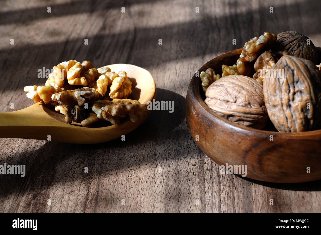 Whole walnuts and kernel walnuts in wooden bowl and wooden spoon on ...