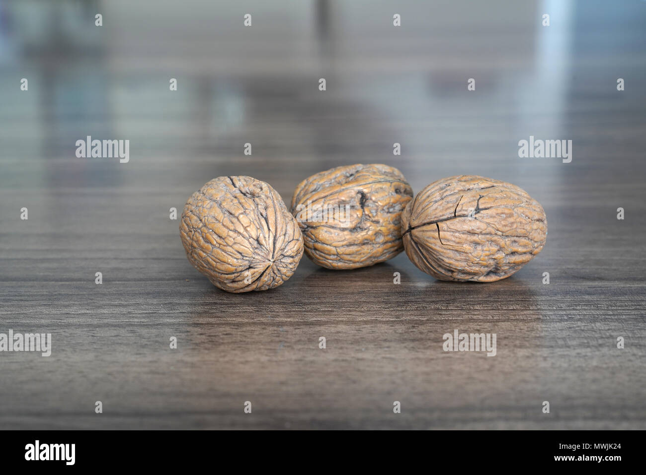 Three walnuts on dark walnut table background Stock Photo - Alamy
