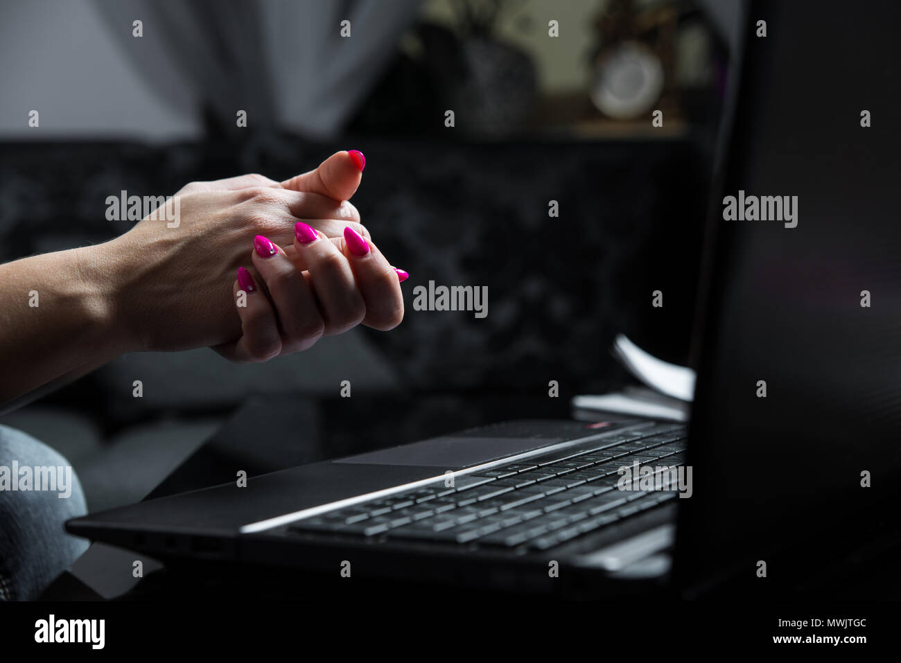 Woman working at home, typing on a laptop keyboard. Evening, hard work ...