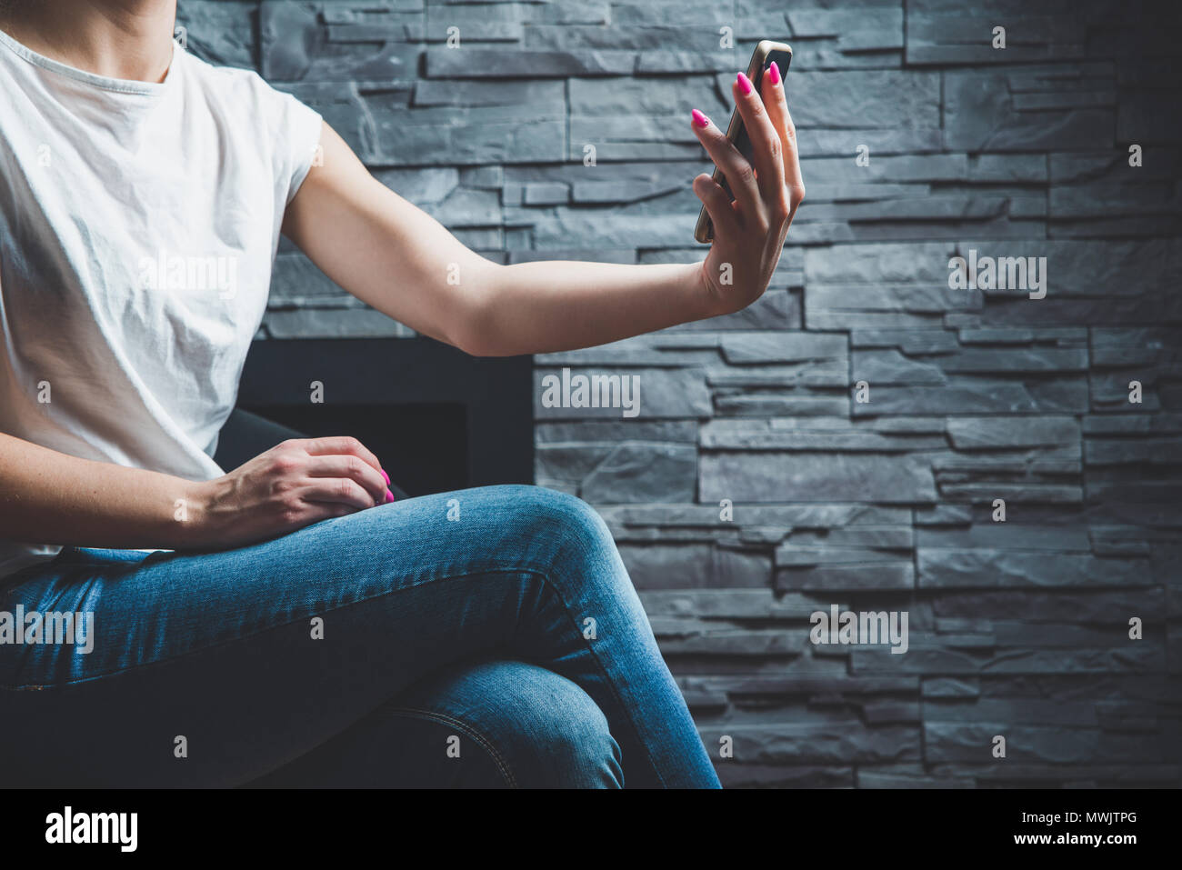 The woman is sitting on a chair, she has a telephone stretched out, she ...