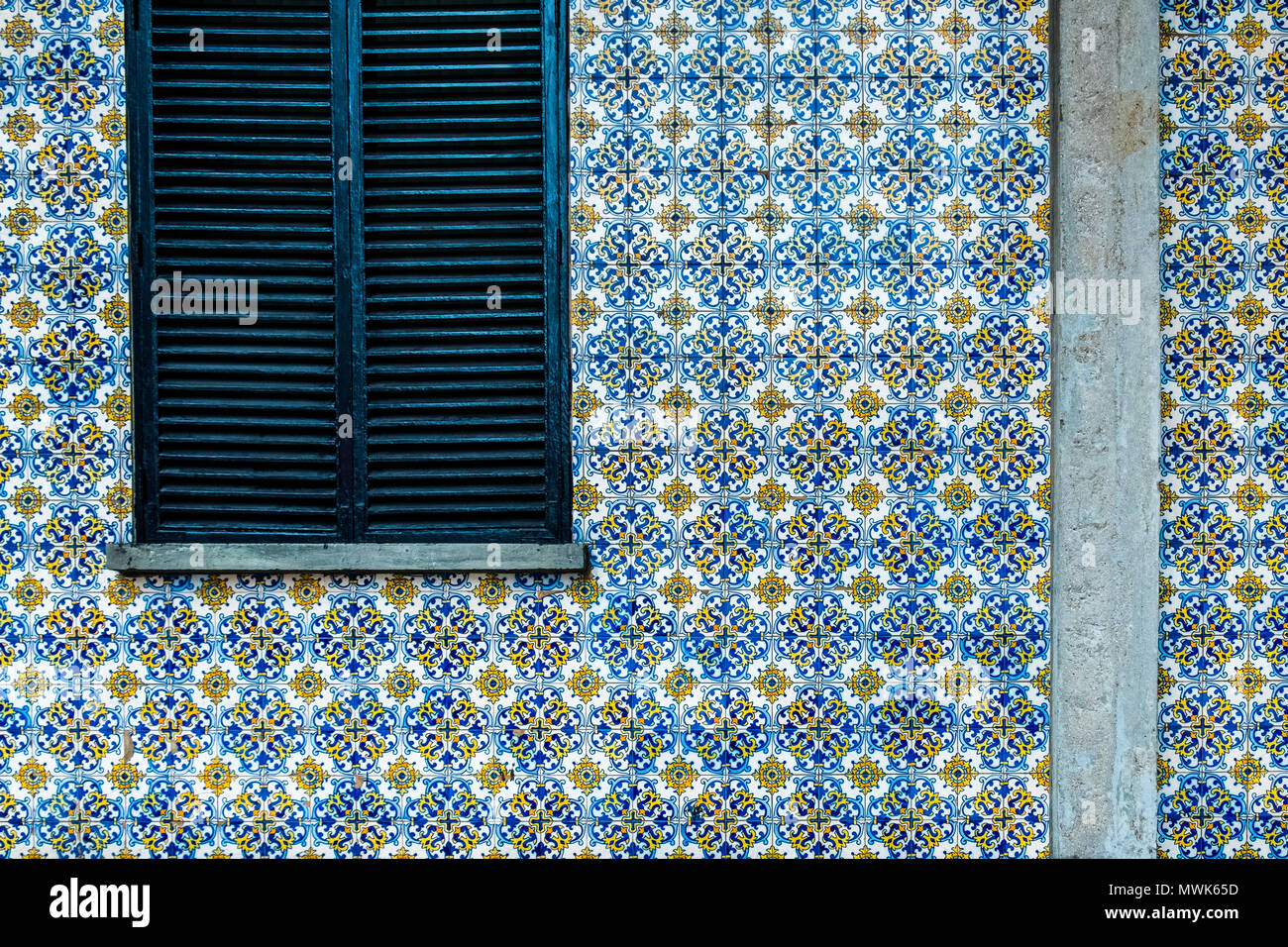 Building wall decorated old ceramic tile. Closed window with wooden ...