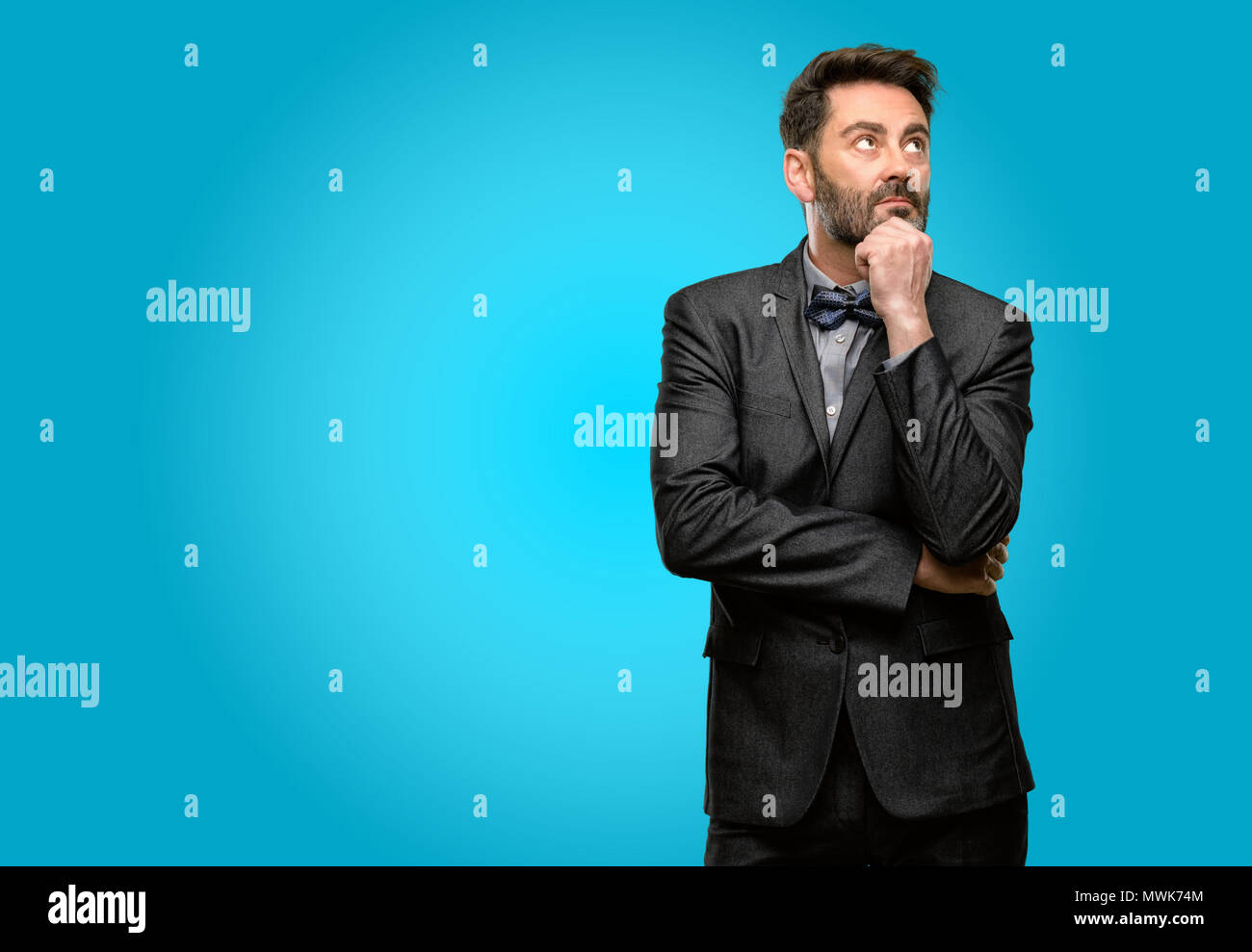 Middle age man, with beard and bow tie thinking and looking up ...