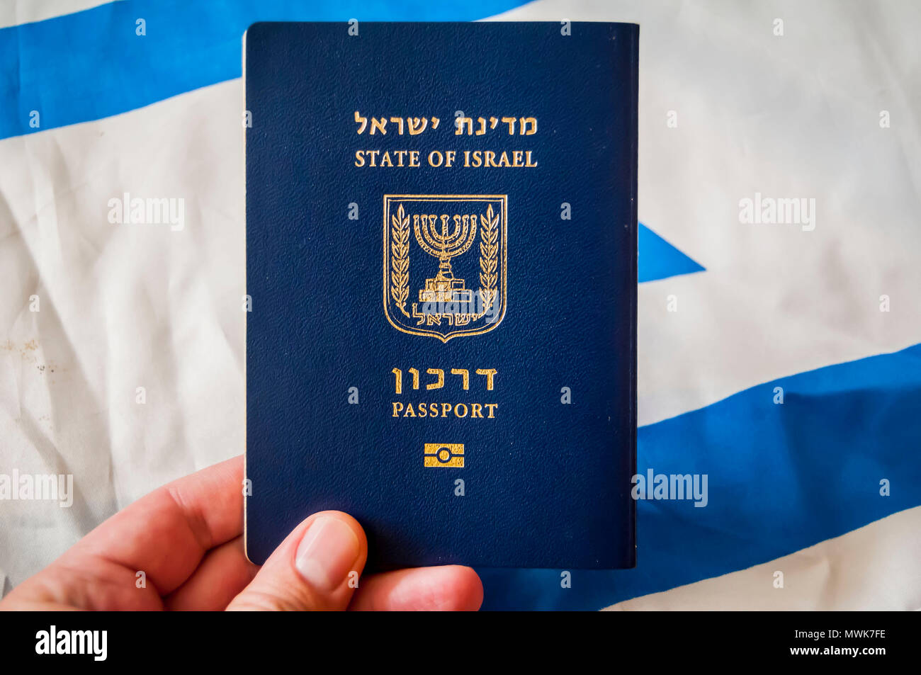Hand holding the passport of the State of Israel, Israeli flag on the ...