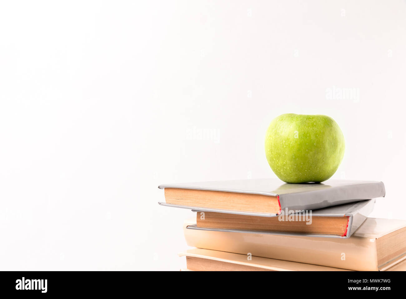 Apple on top of pile of books isolated on white Stock Photo - Alamy