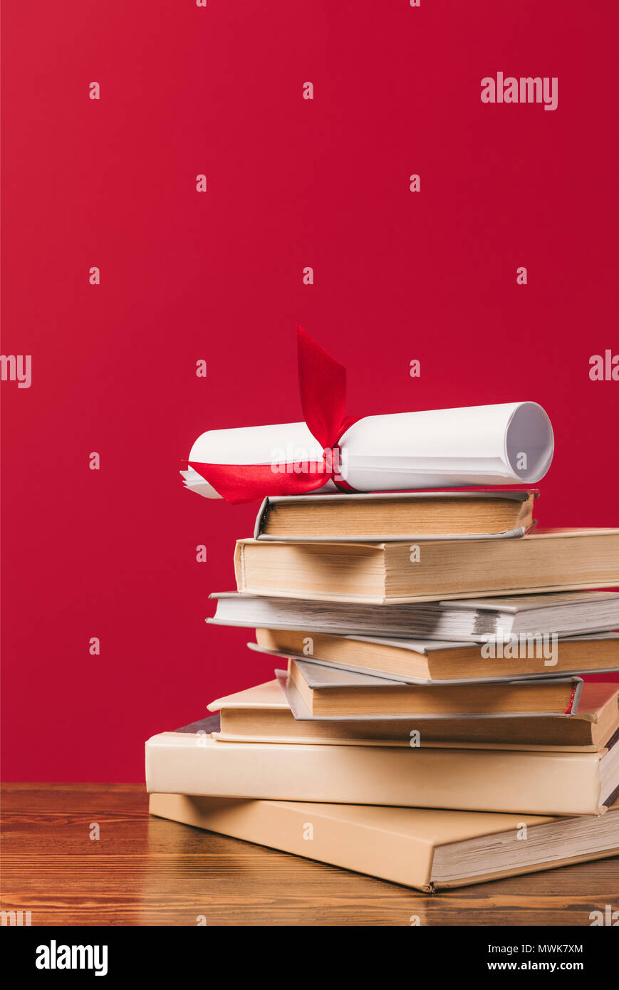 Diploma on top of stack of books on red Stock Photo - Alamy