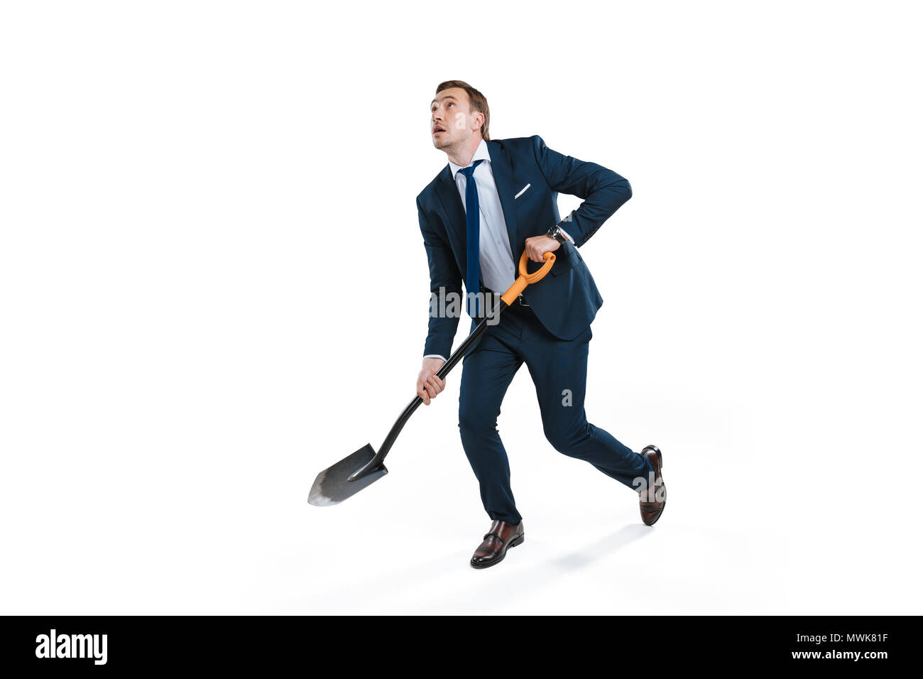 young businessman in formal wear digging with shovel and looking up ...