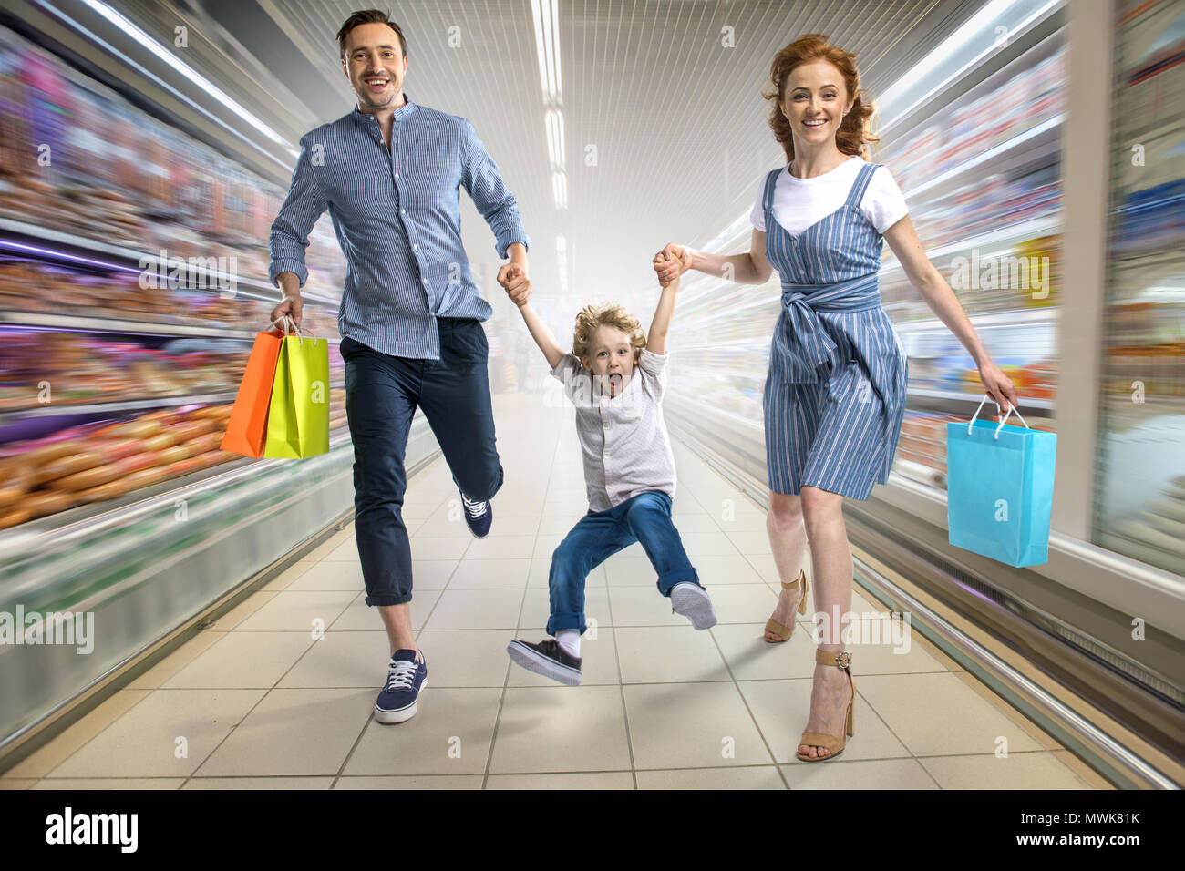 smiling parents with shopping bags holding hands together with excited ...
