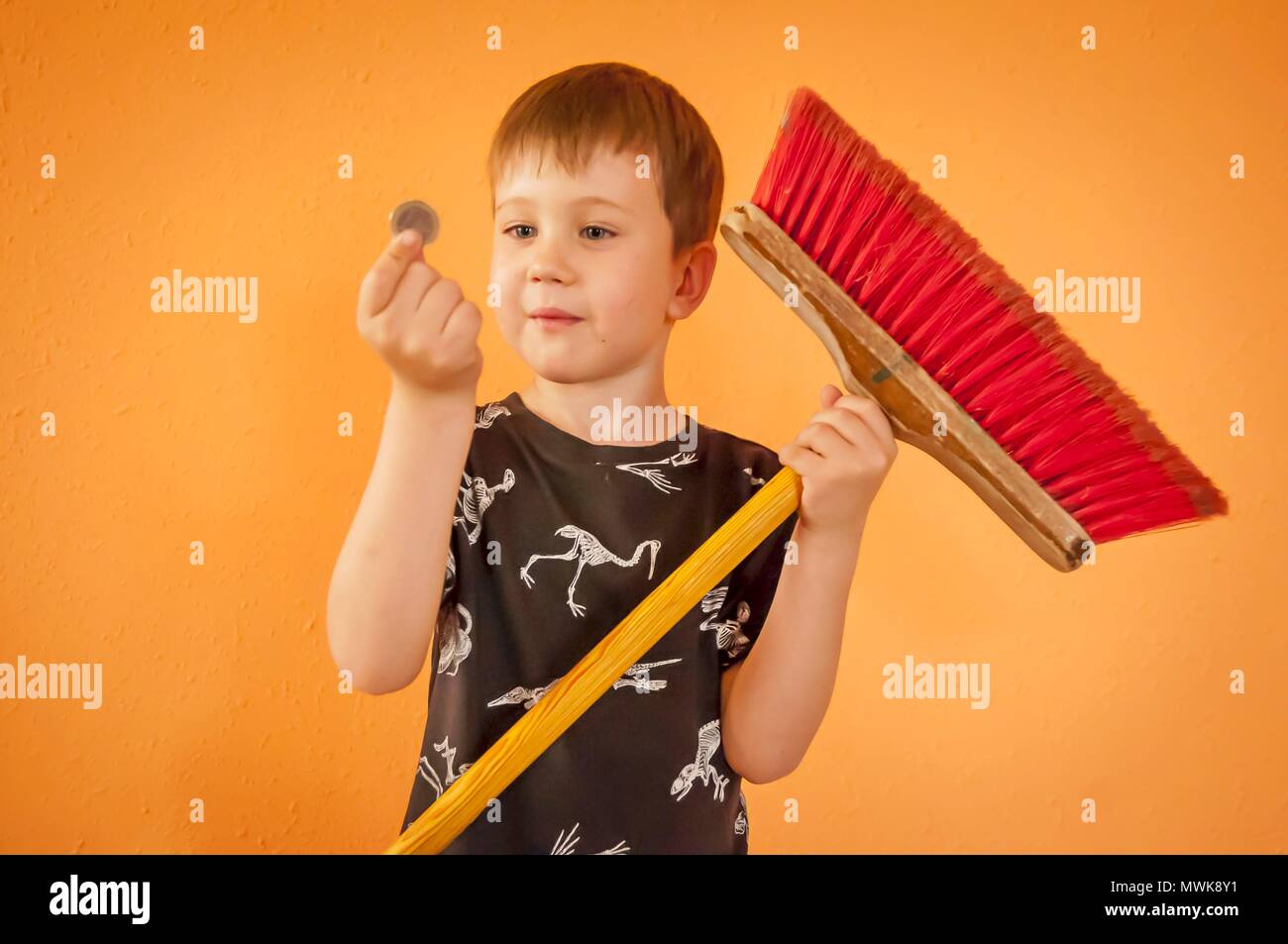 Cute happy little child with a broom earn his first money by doing ...