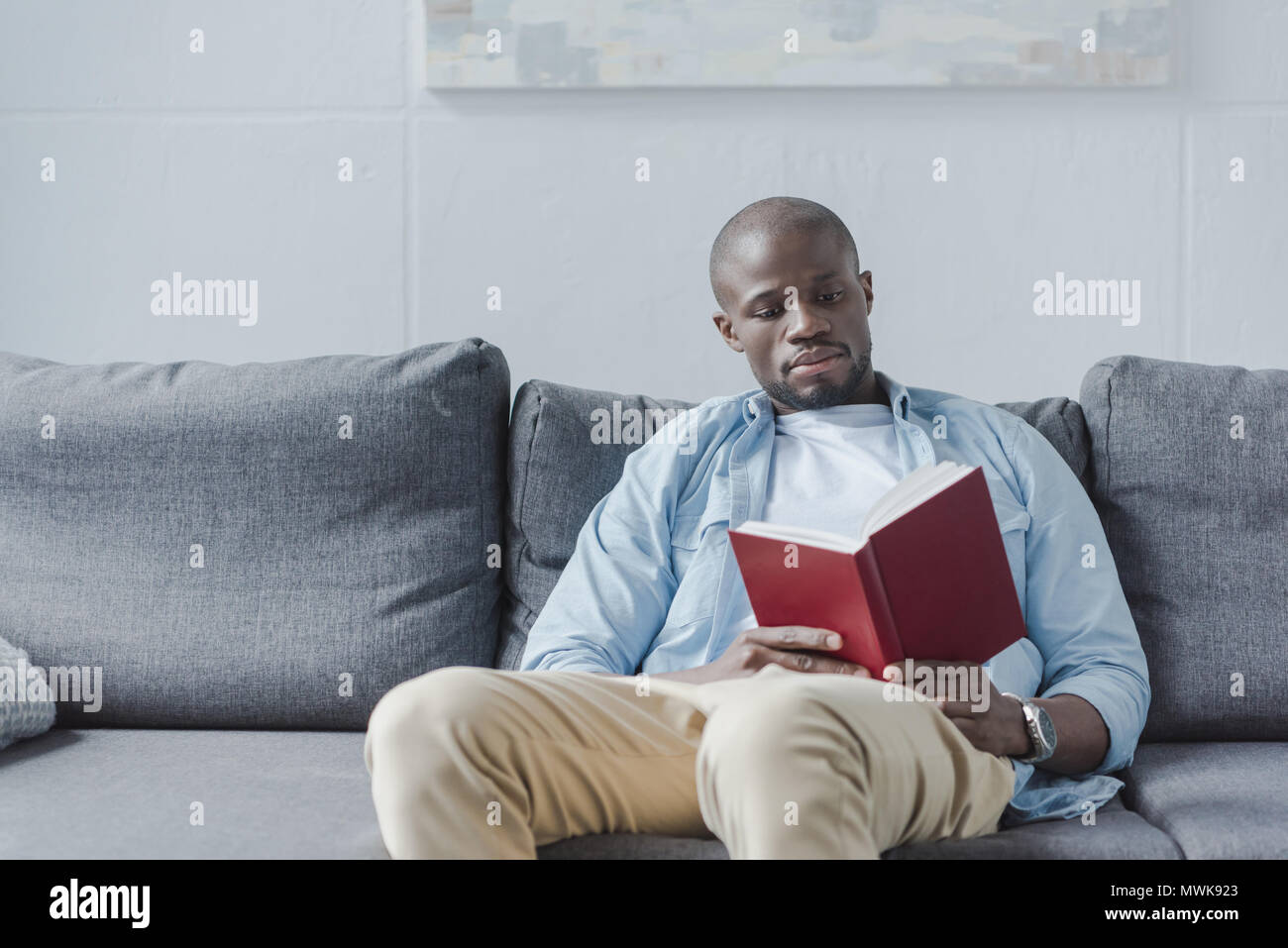 Handsome african american man reading book at home Stock Photo - Alamy
