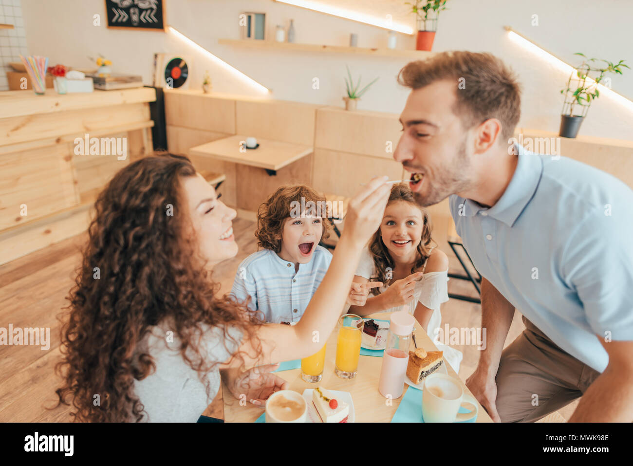 beautiful young family eating sweets in cafe with modern trendy ...