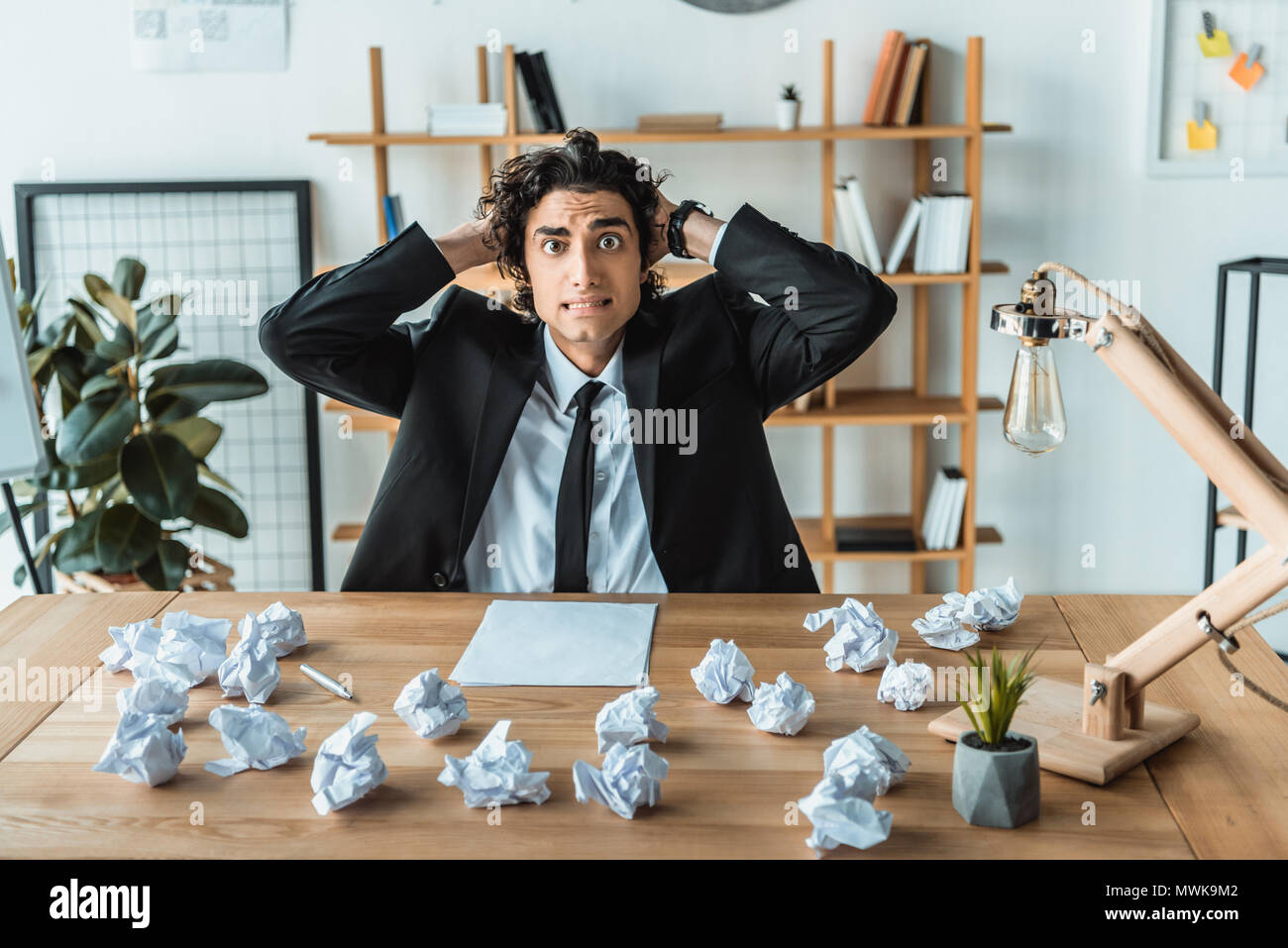 portrait of overworked businessman sitting at workplace full of ...