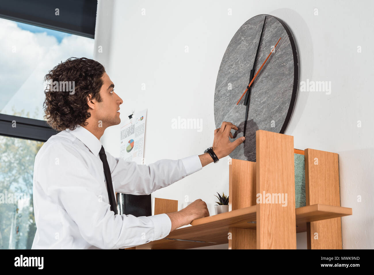 side view of young businessman setting time on clock in office Stock ...