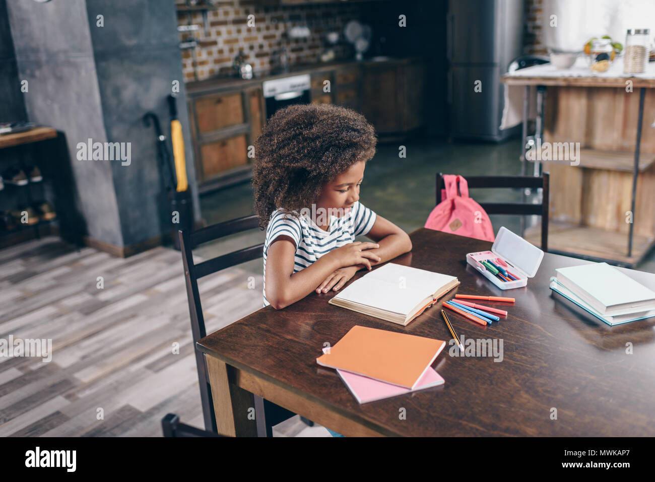 Little girl reading a book at the kitchen table Stock Photo - Alamy