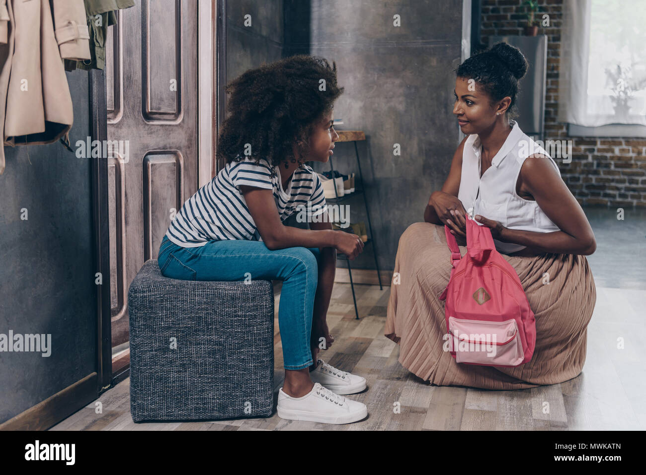 Little girl preparing to school with her mother holding her backpack ...