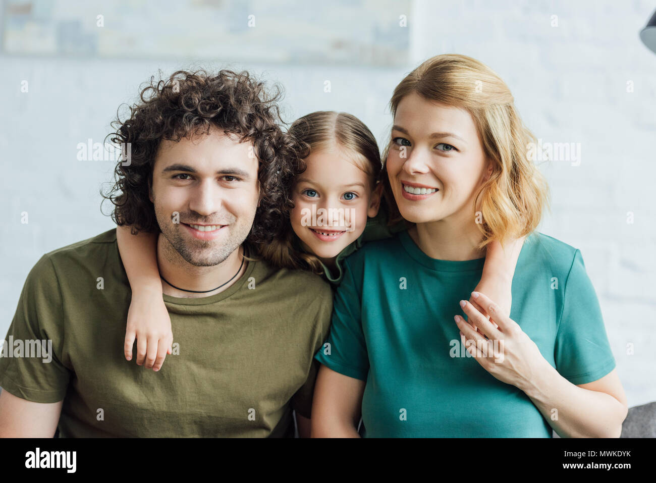 happy family with one child embracing and smiling at camera Stock Photo ...