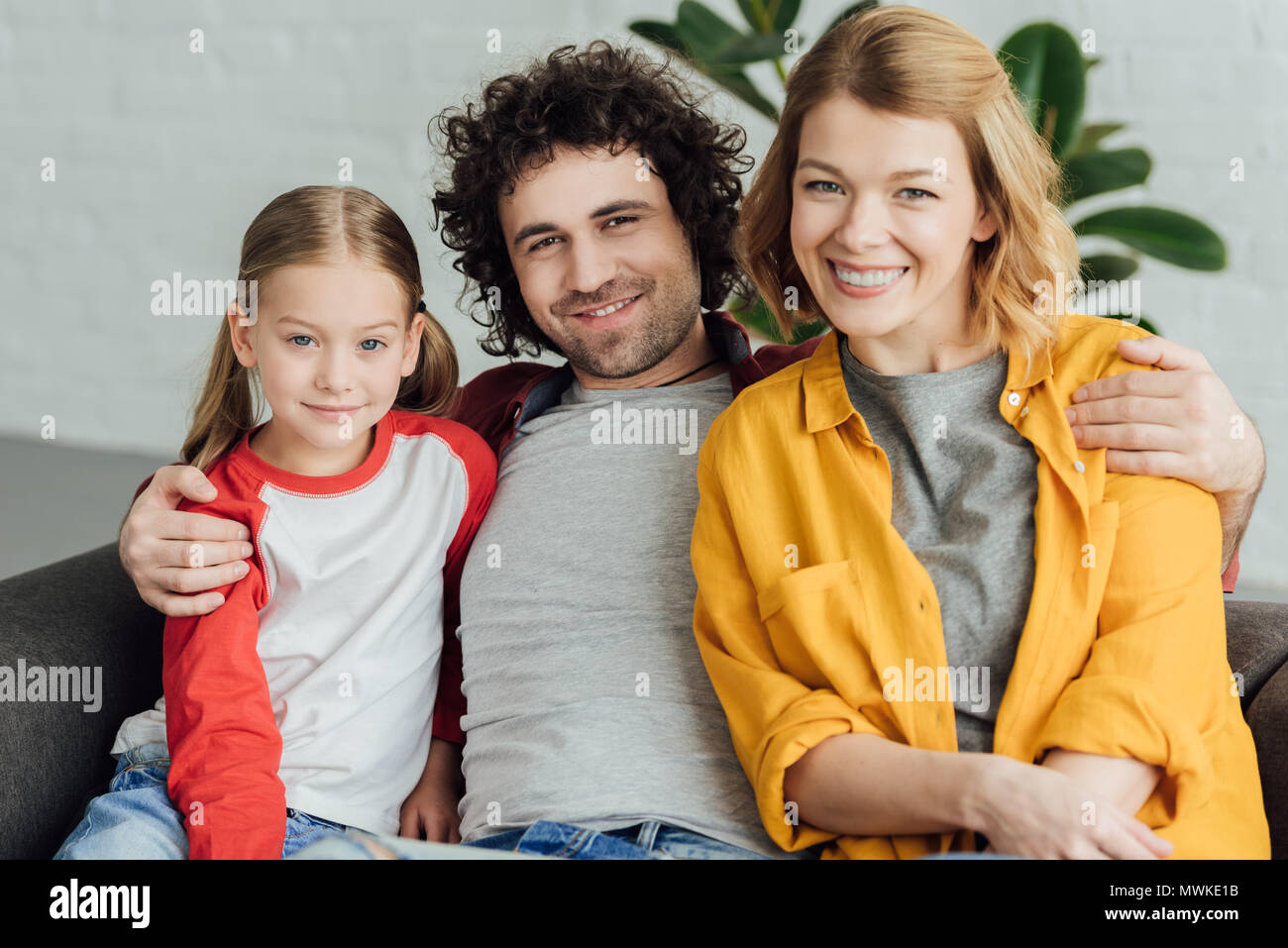 happy parents with cute little child sitting together and smiling at ...