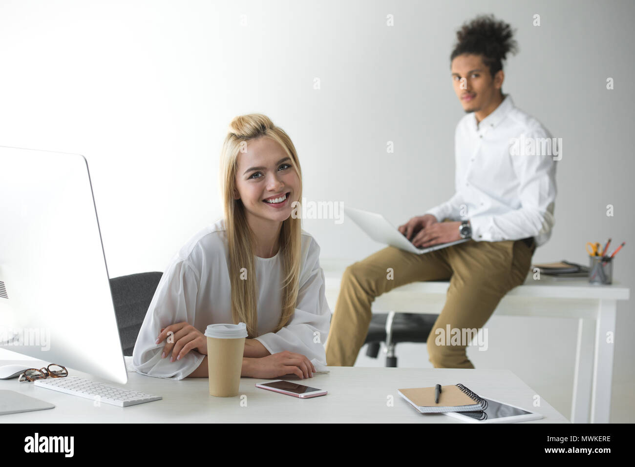 beautiful young businesswoman smiling at camera dand male colleague ...