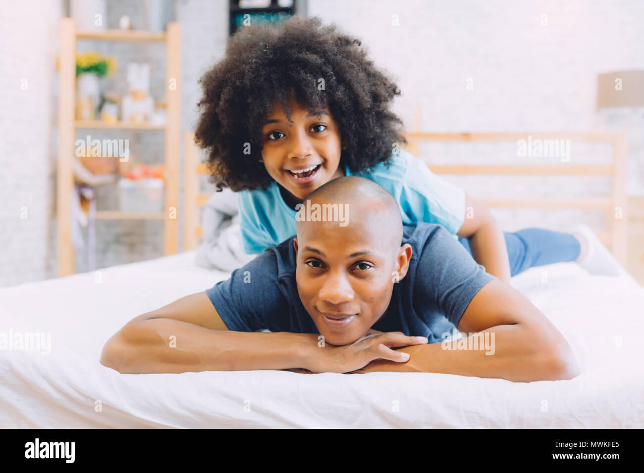 African American family of two, child sitting on father's back at home ...