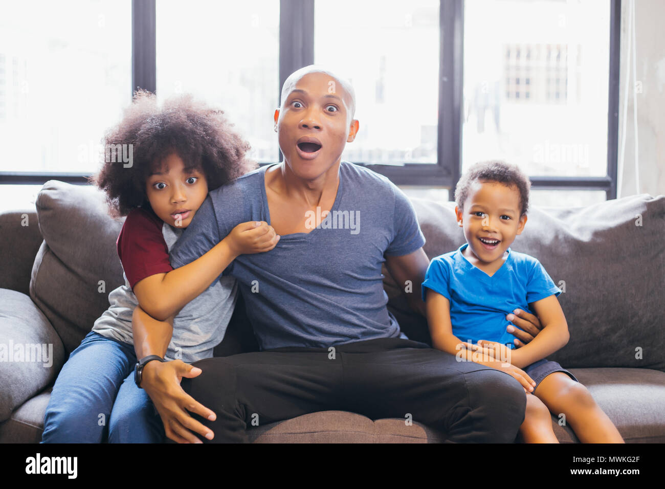 Whole family of African American watching and staring horror movie on ...