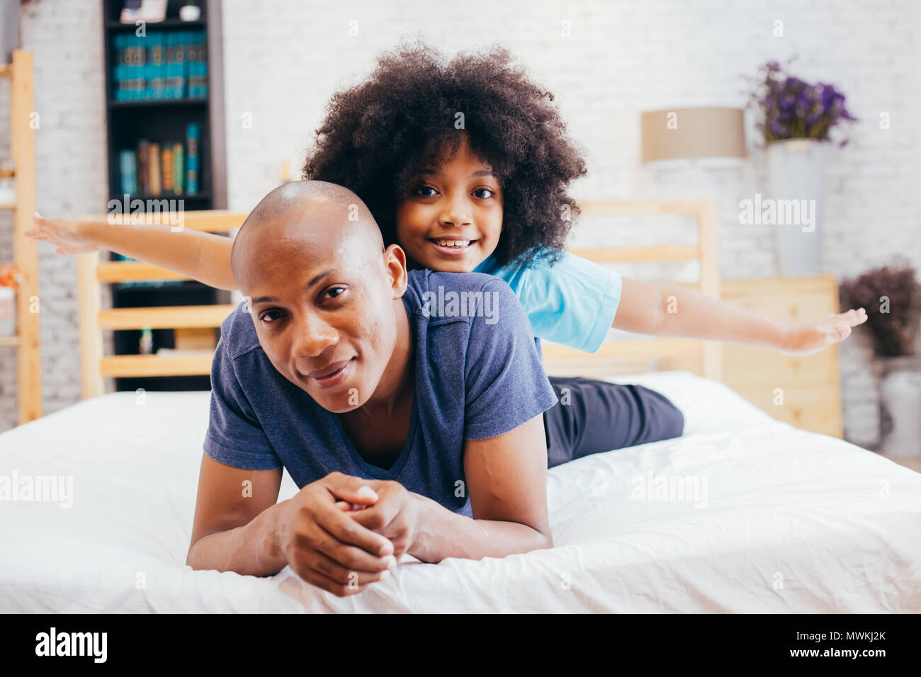 African American family of two, child sitting on father's back at home ...