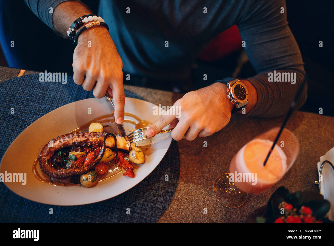 The man eat tentacle of the octopus in the restaurant Stock Photo - Alamy