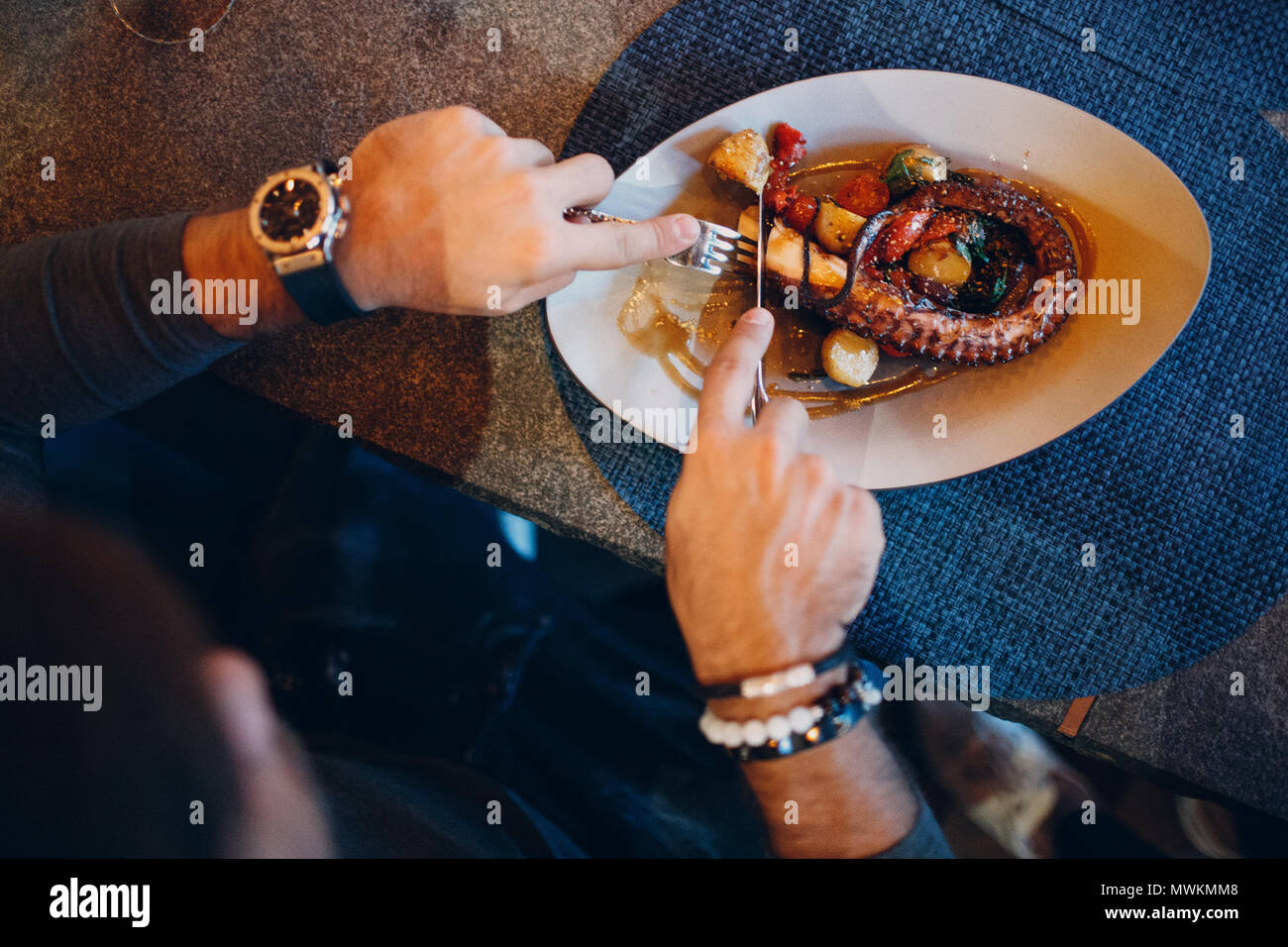The man eat tentacle of the octopus in the restaurant Stock Photo - Alamy
