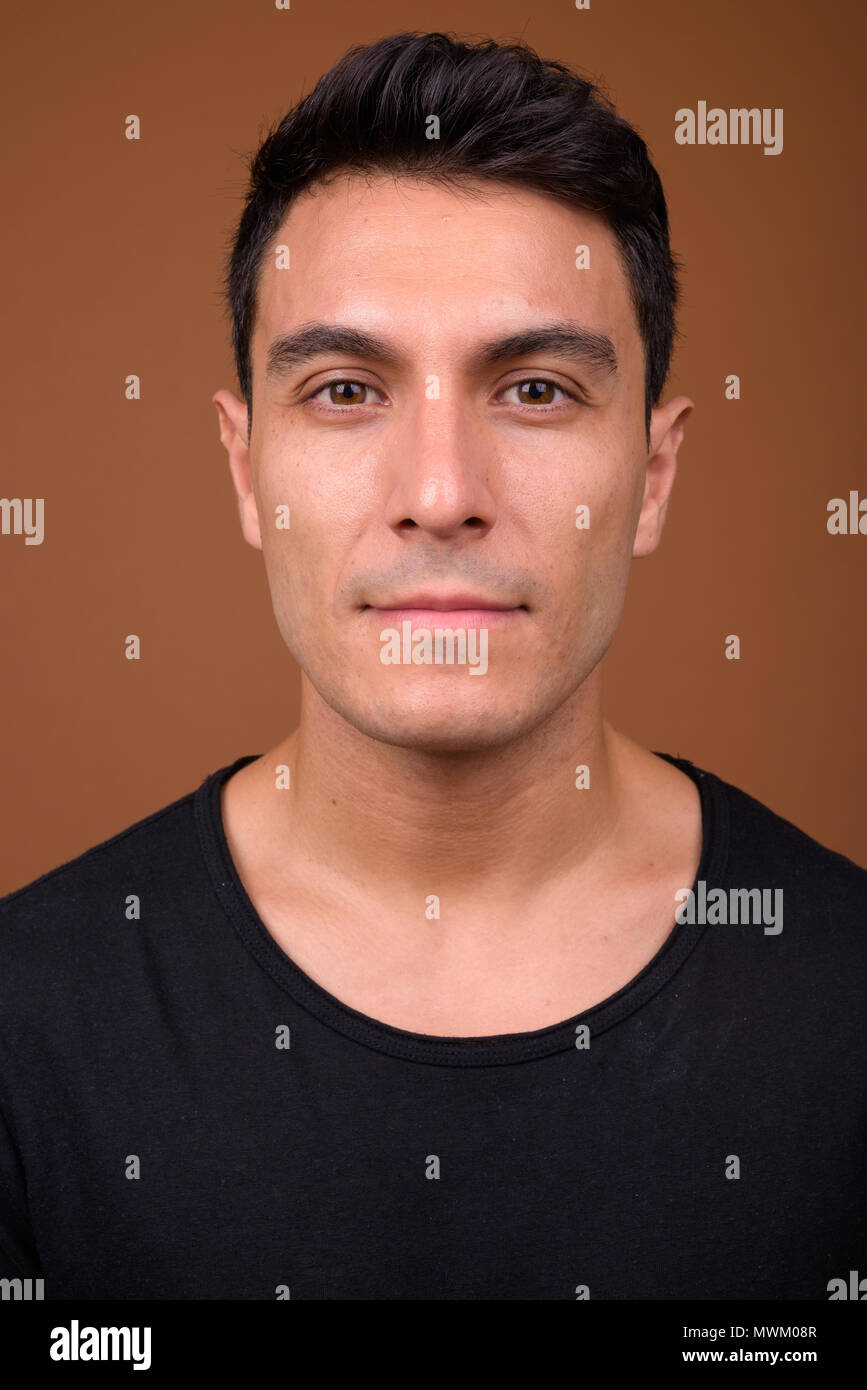 Young handsome Hispanic man against brown background Stock Photo - Alamy